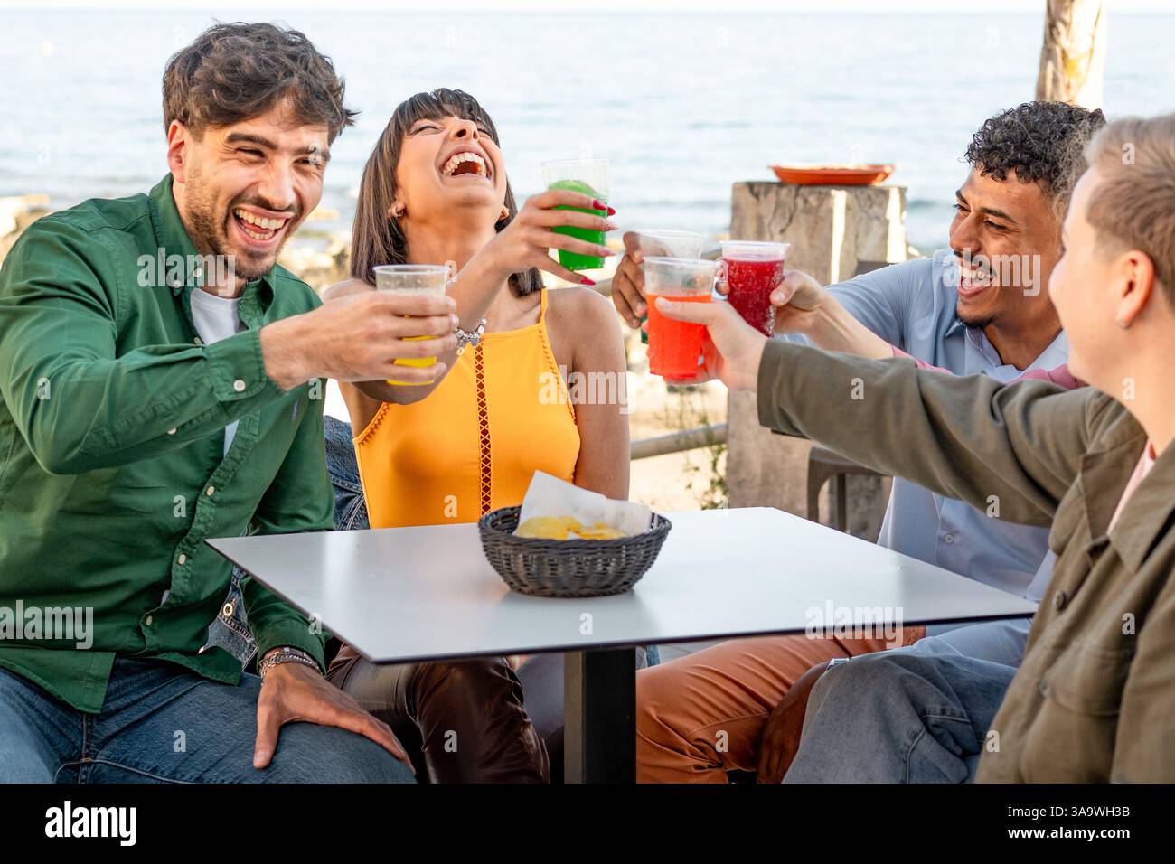 A group of diverse young friends laughing and toasting with colorful ...