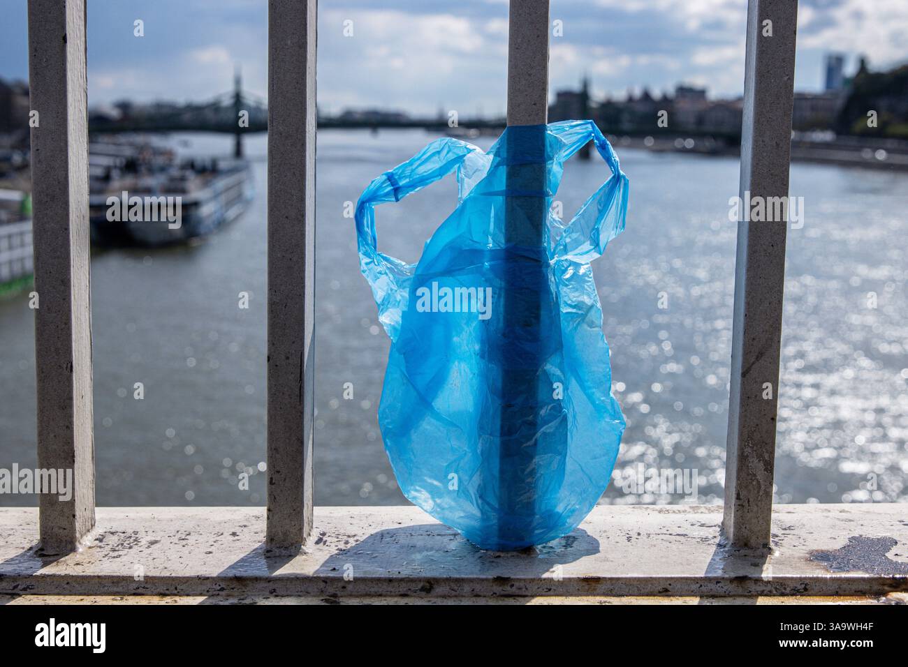 Swaying in the wind blue plastic bag stuck on a bridge railing ...
