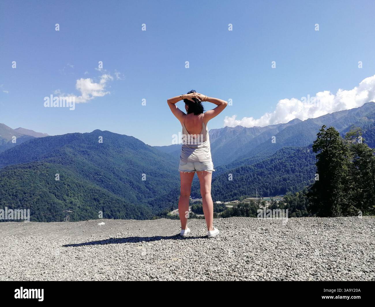 Individual stands with hands on head, gazing at a vast mountain ...