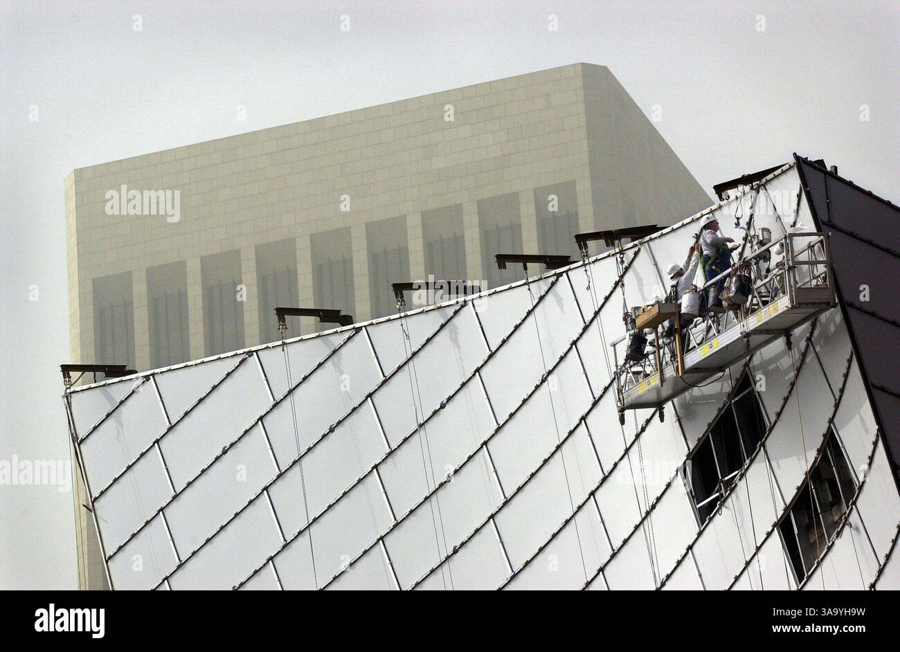 A high rise looms in the background as workers prepare to install ...