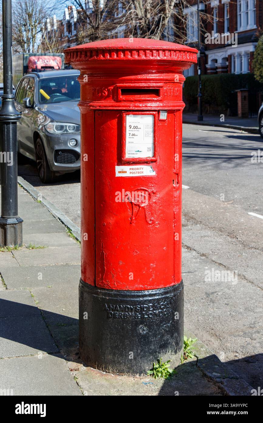 Traditional red circular Victorian post box on a residential street in ...