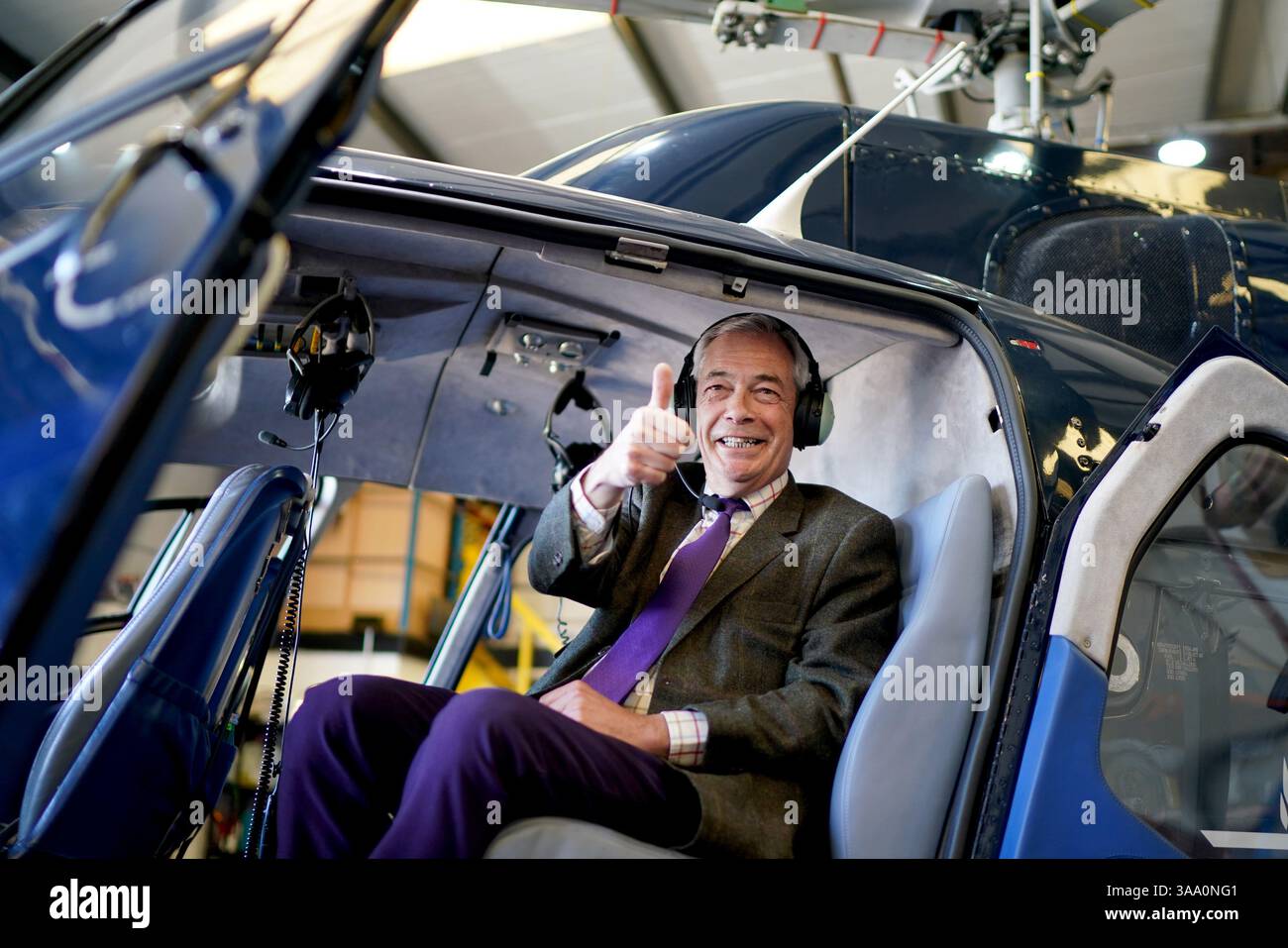Reform UK leader Nigel Farage sits in a helicopter at a hangar, while ...