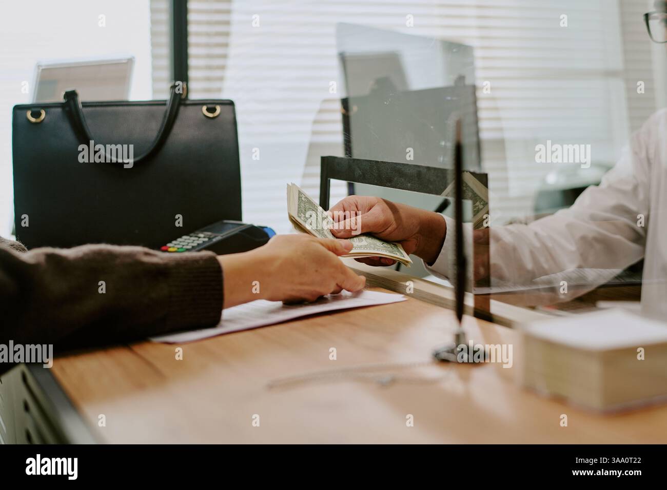 Two people exchanging money over a counter, with cash being handed ...