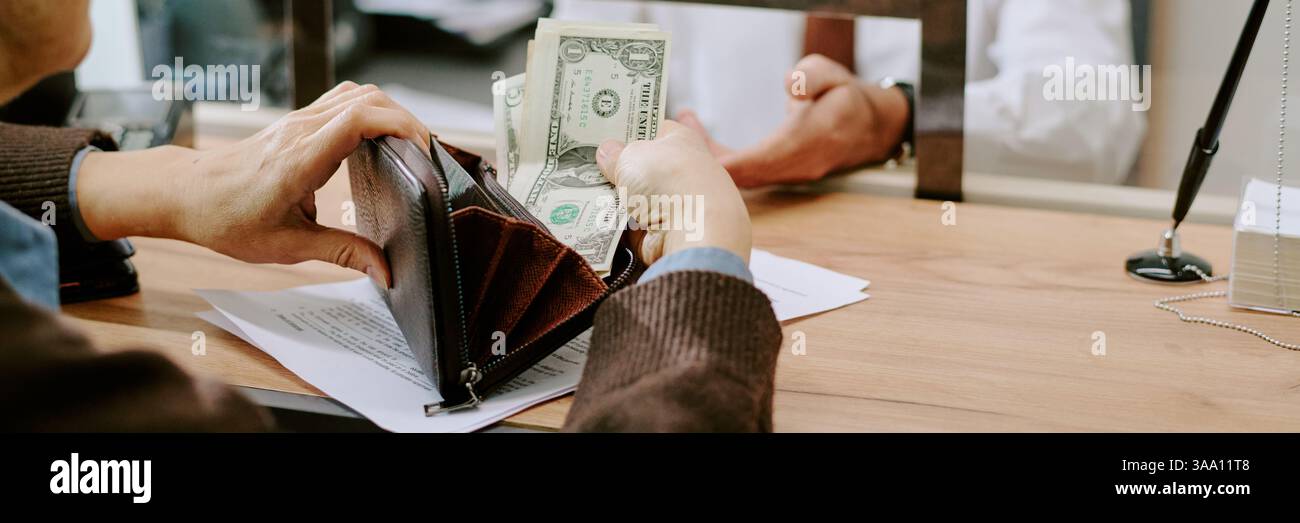 Woman counting money while sitting at desk with wallet open, holding ...