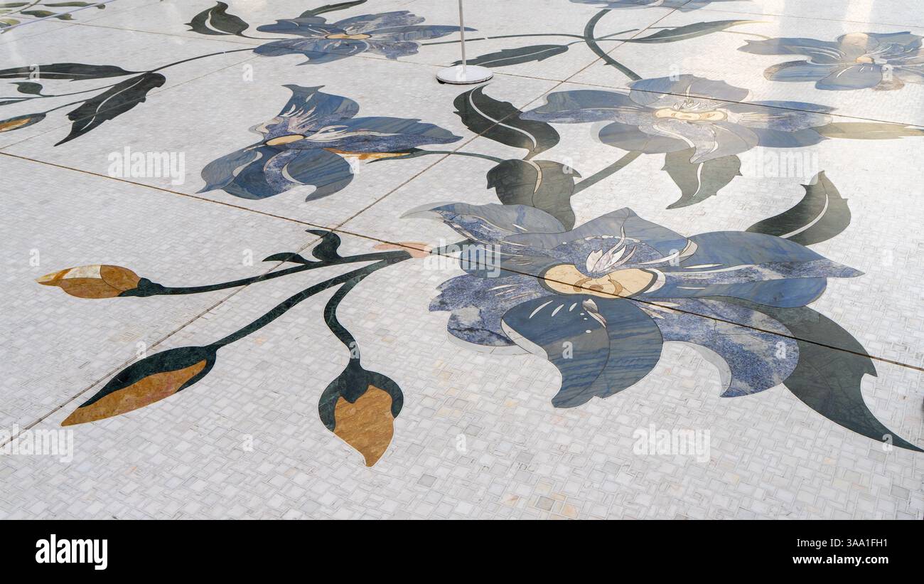 Mosaic of multicolored stone in form of blue flower on white marble ...
