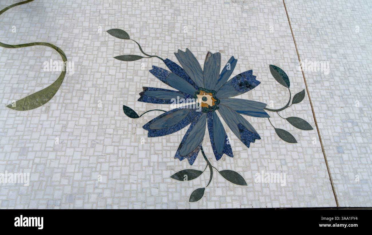 Mosaic of multicolored stone in form of blue flower on white marble ...