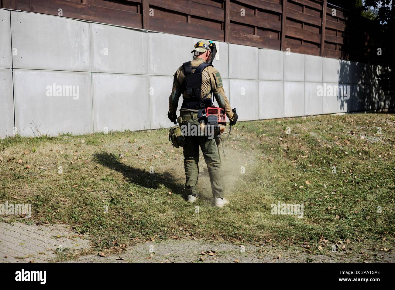 Back view of man removing grass with a trimmer. Gardening care tools ...
