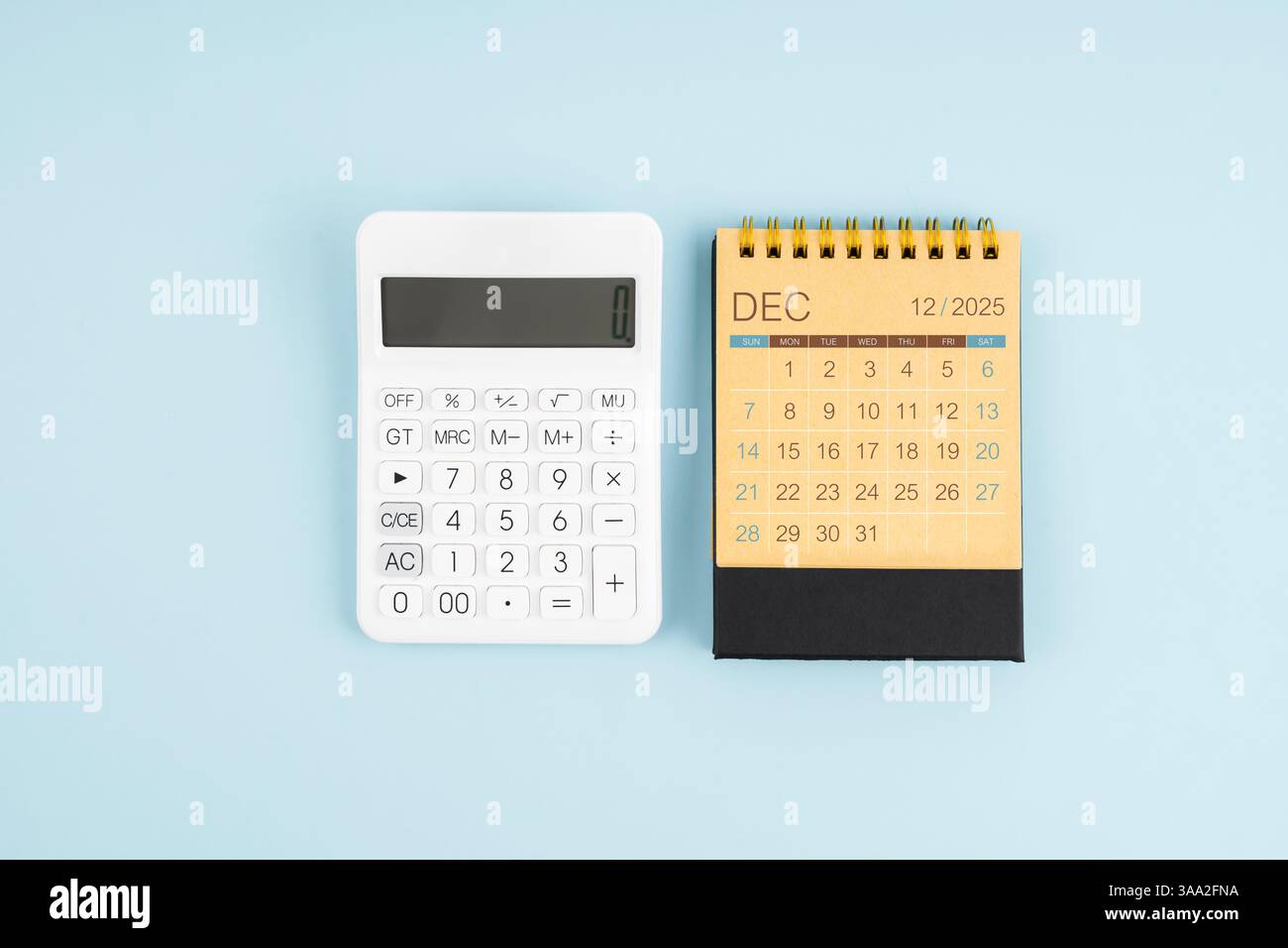 December 2025 desk calendar and calculator on blue color background ...
