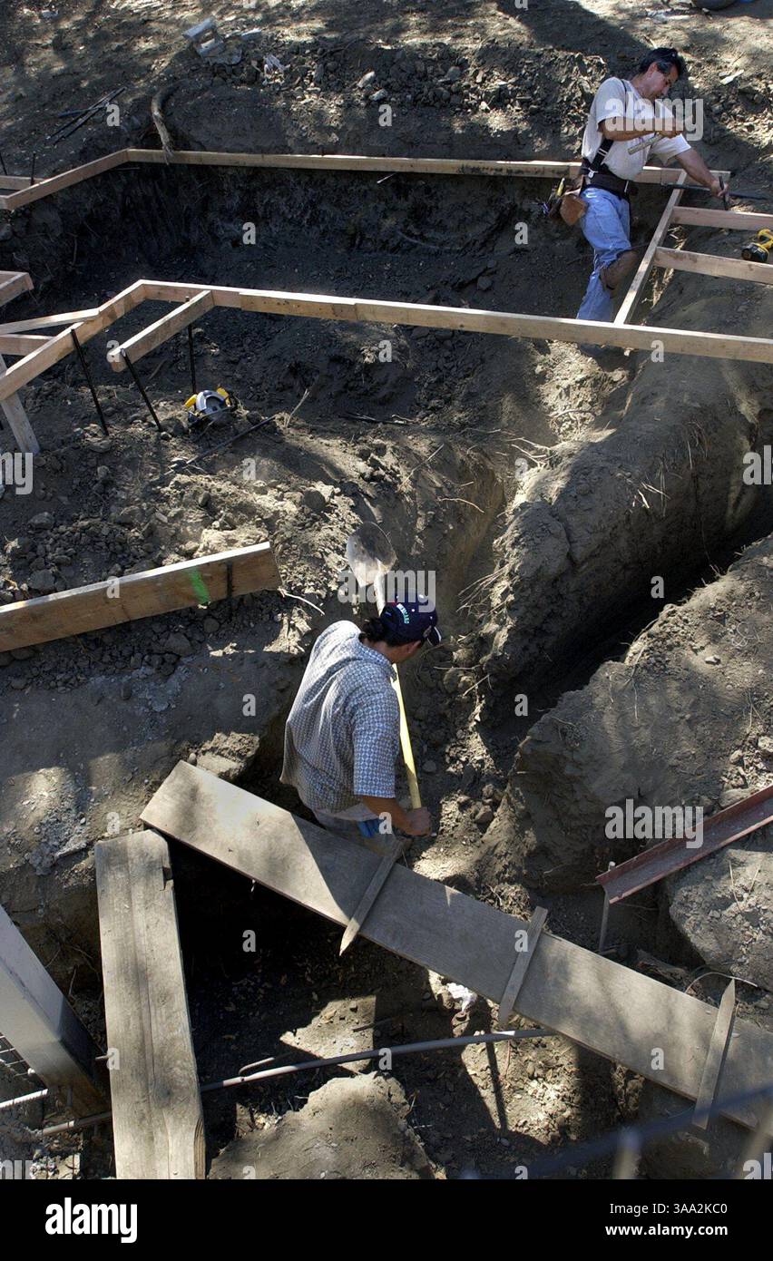 Construction workers dig trenches for plumbing and set up the framework ...