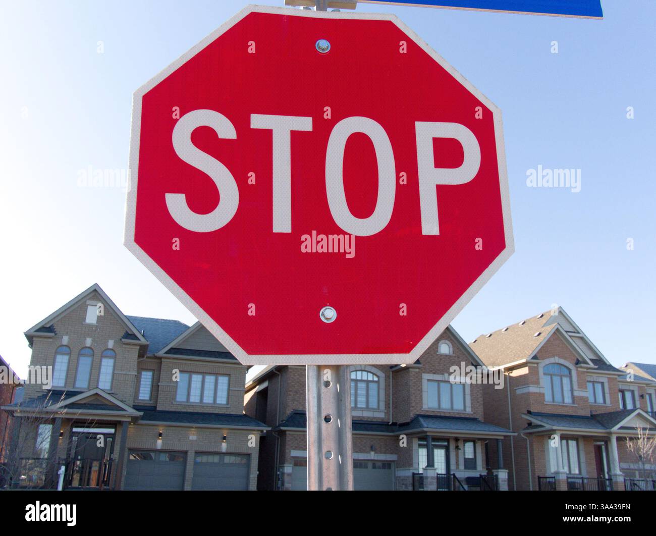 A bright, bold stop sign stands firmly in front of modern suburban ...