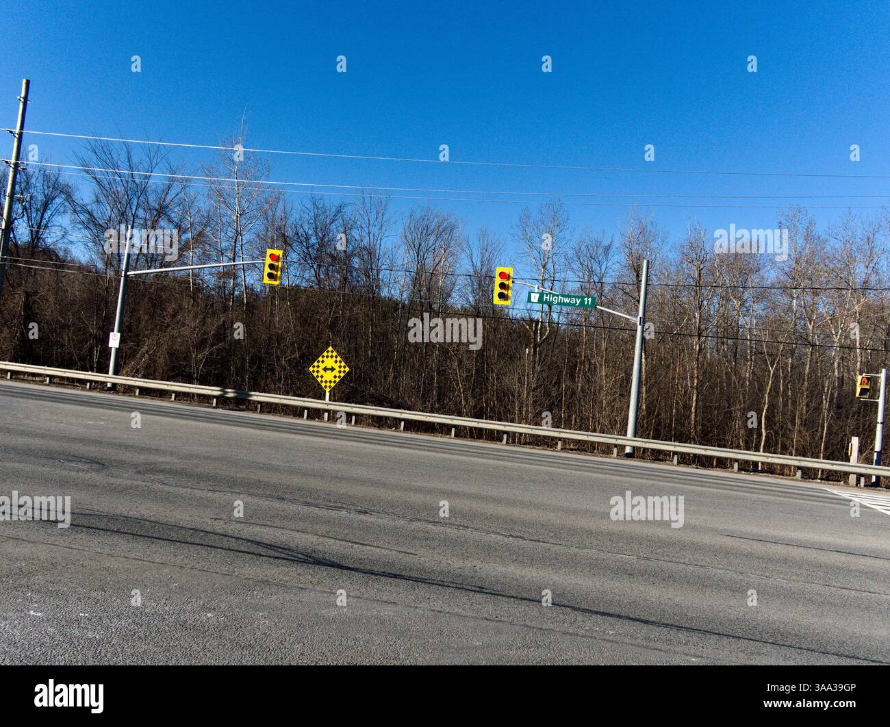 A traffic intersection with red lights and road signs on Highway 11. A ...