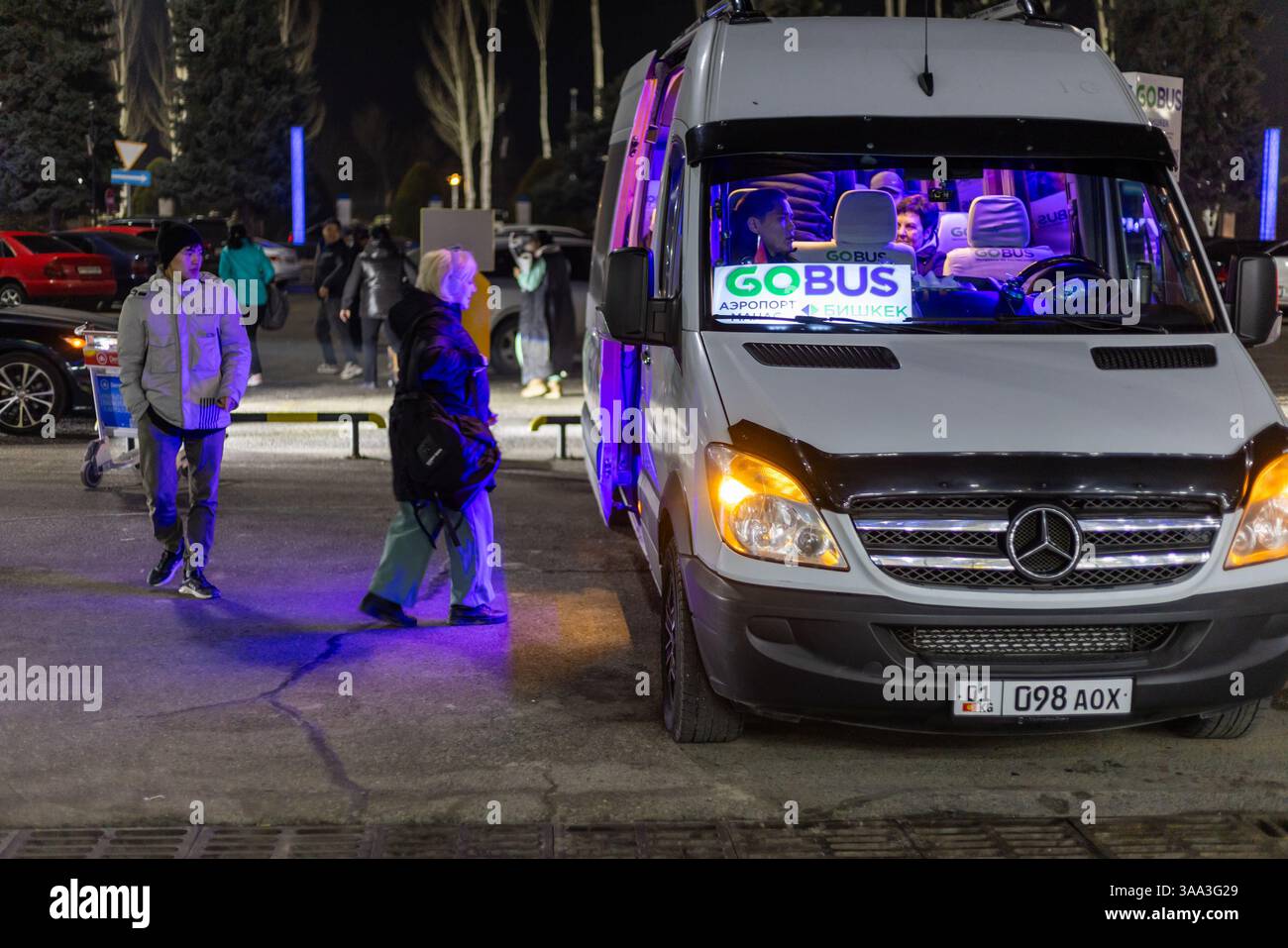 Passengers near GoBus Shuttle bus at night in front of Manas airport ...