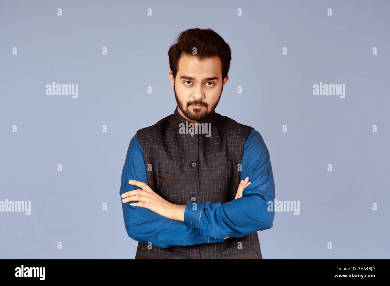 Portrait of serious Indian man with crossed arms on lilac background ...