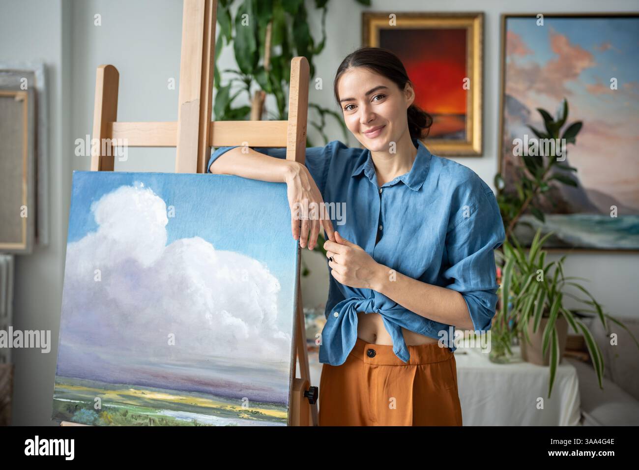 Portrait proud happy woman artist with new painting of sky and nature ...