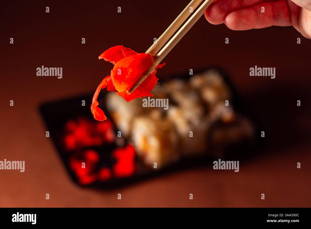 Chopsticks taking portion of sushi roll. Sushi rolls with salmon cream cheese and cucumber in ...