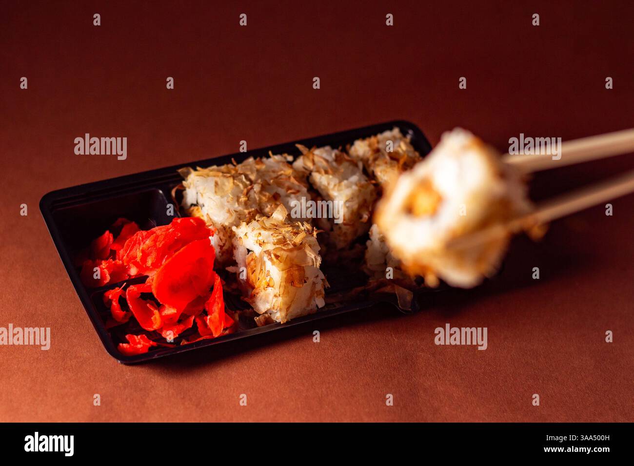 Chopsticks taking portion of sushi roll. Sushi rolls with salmon cream ...