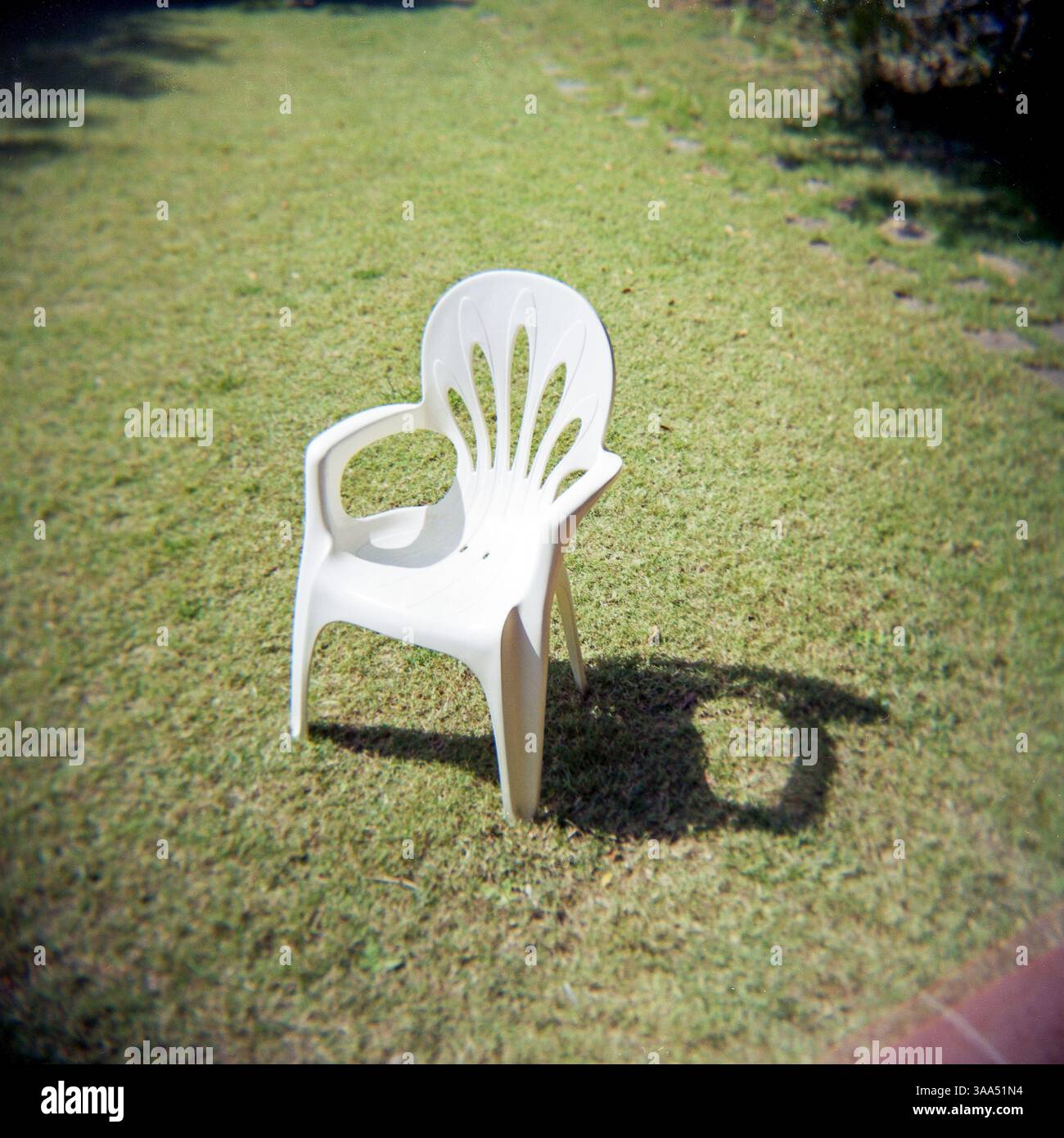 A single white chair isolated on a grassy lawn background, taken with ...