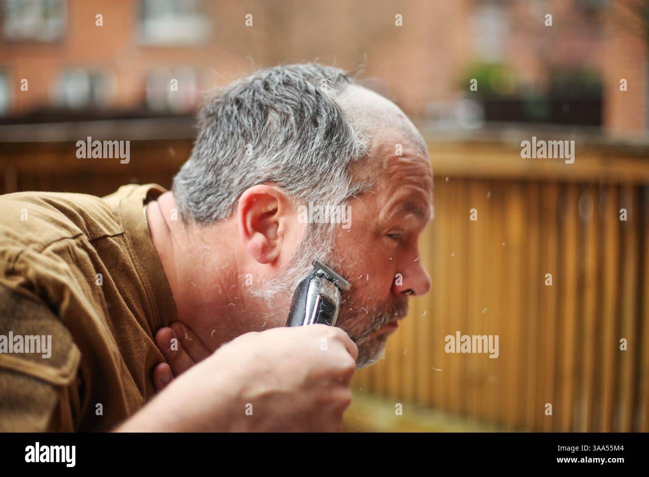 Self-care moment: older man shaving his beard outside, hair flying in ...