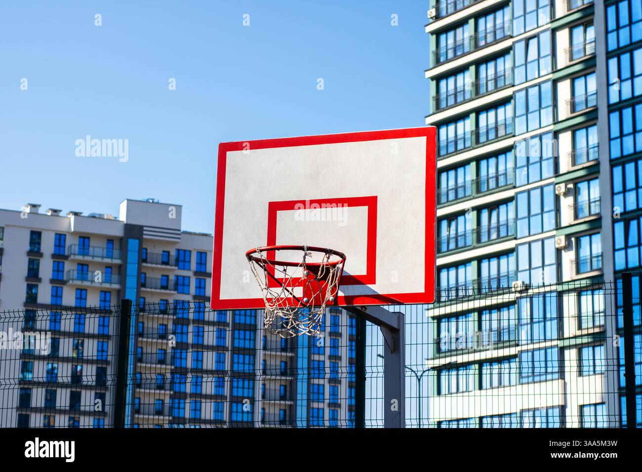 In front of modern architectural buildings, a basketball hoop ...