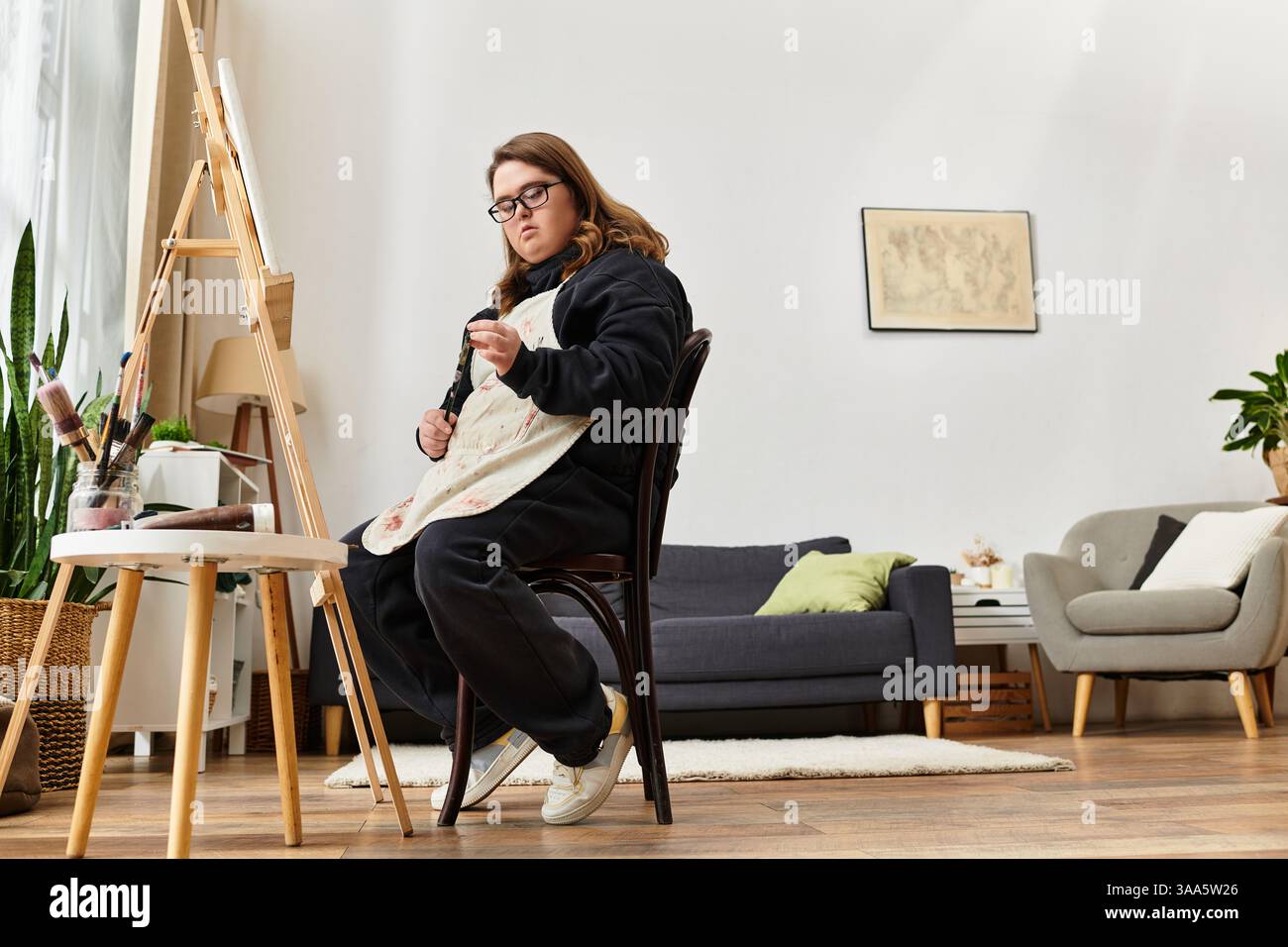 A young woman with Down syndrome paints in a cozy home, expressing her ...