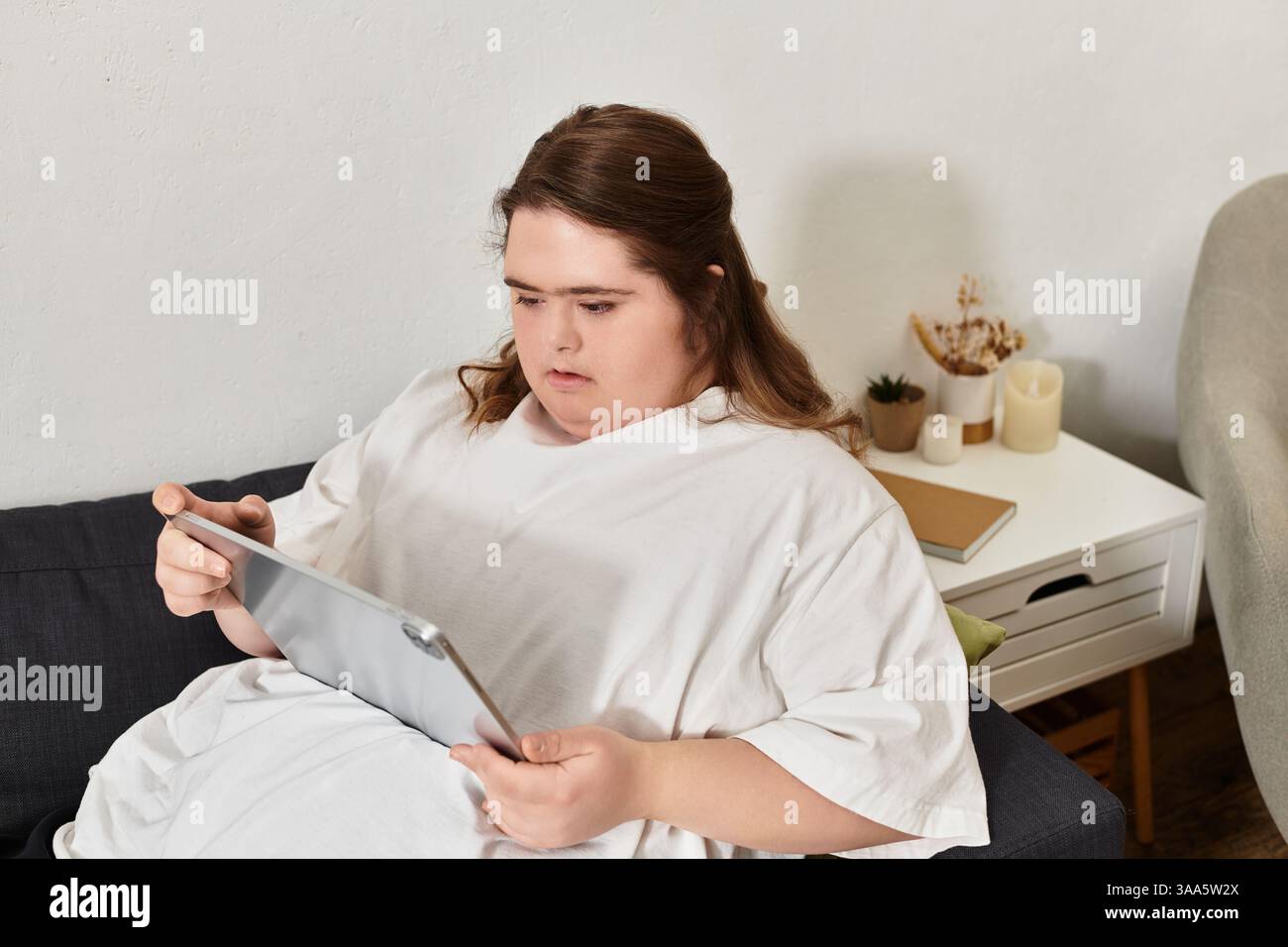 Young woman with Down syndrome relaxes comfortably at home, engaged ...