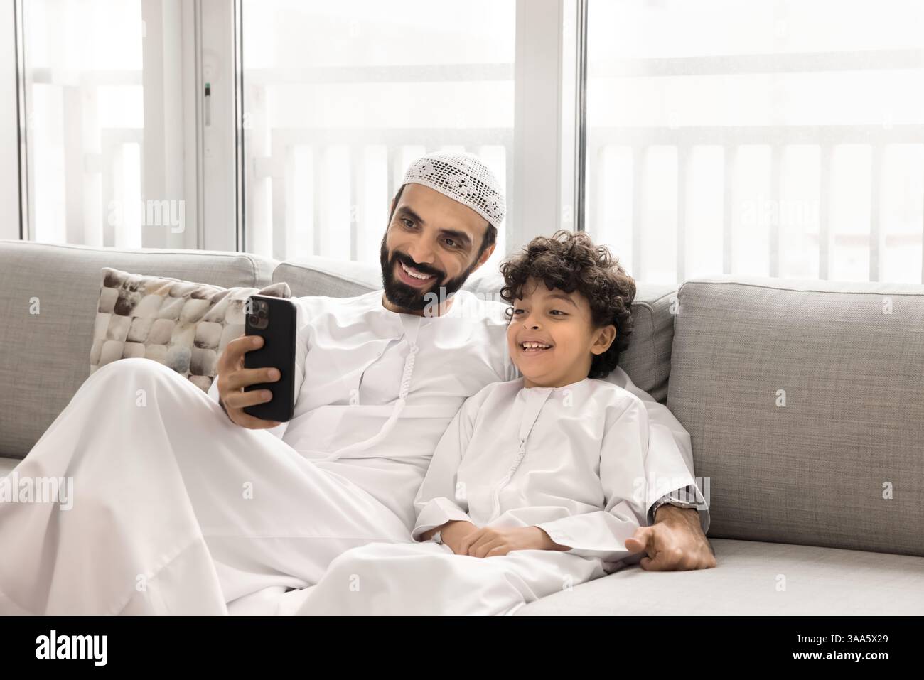 Middle Eastern father his son dressed in kandora using smartphone Stock ...