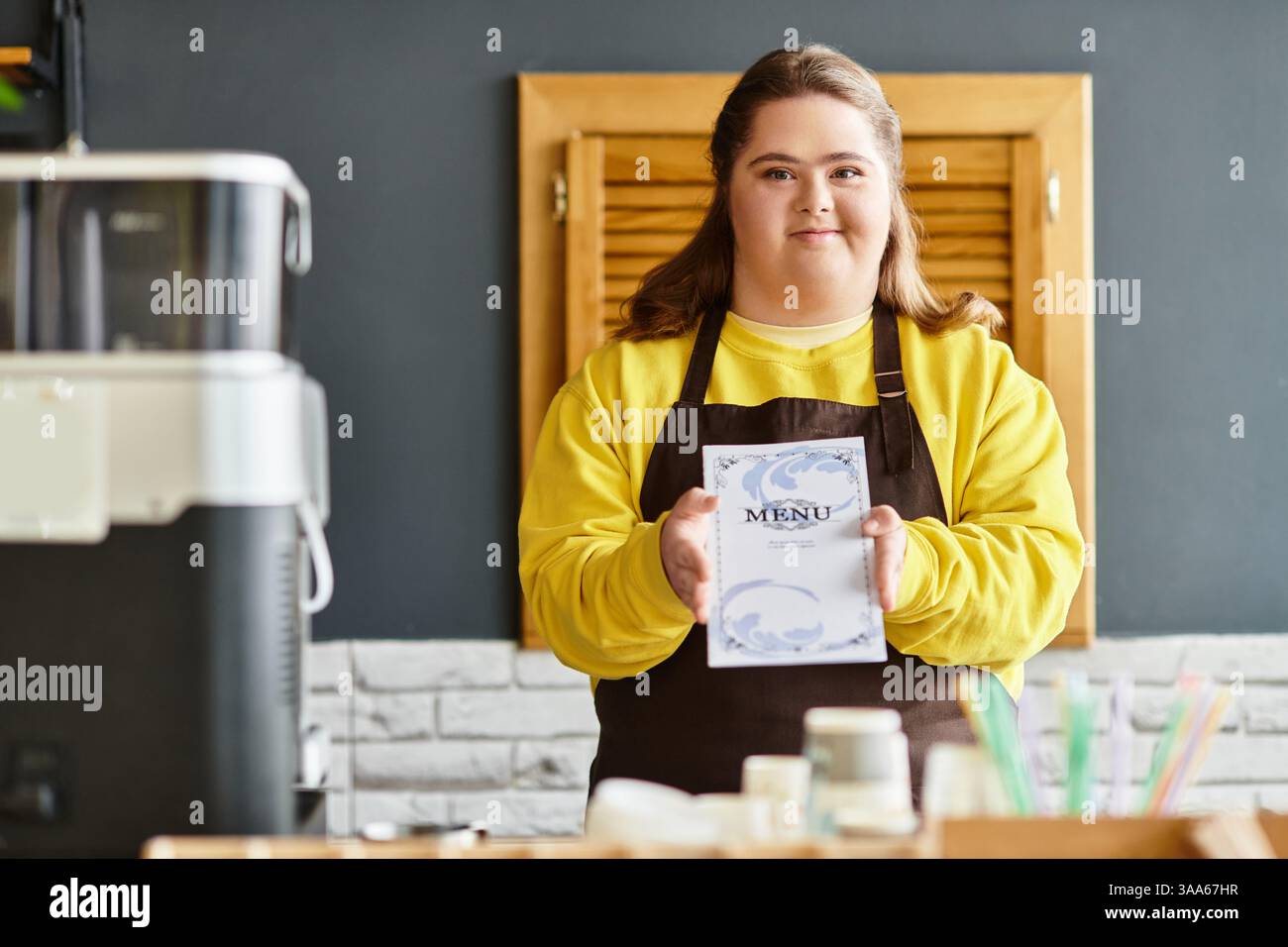A young woman with Down syndrome proudly presents a menu in a warm cafe ...