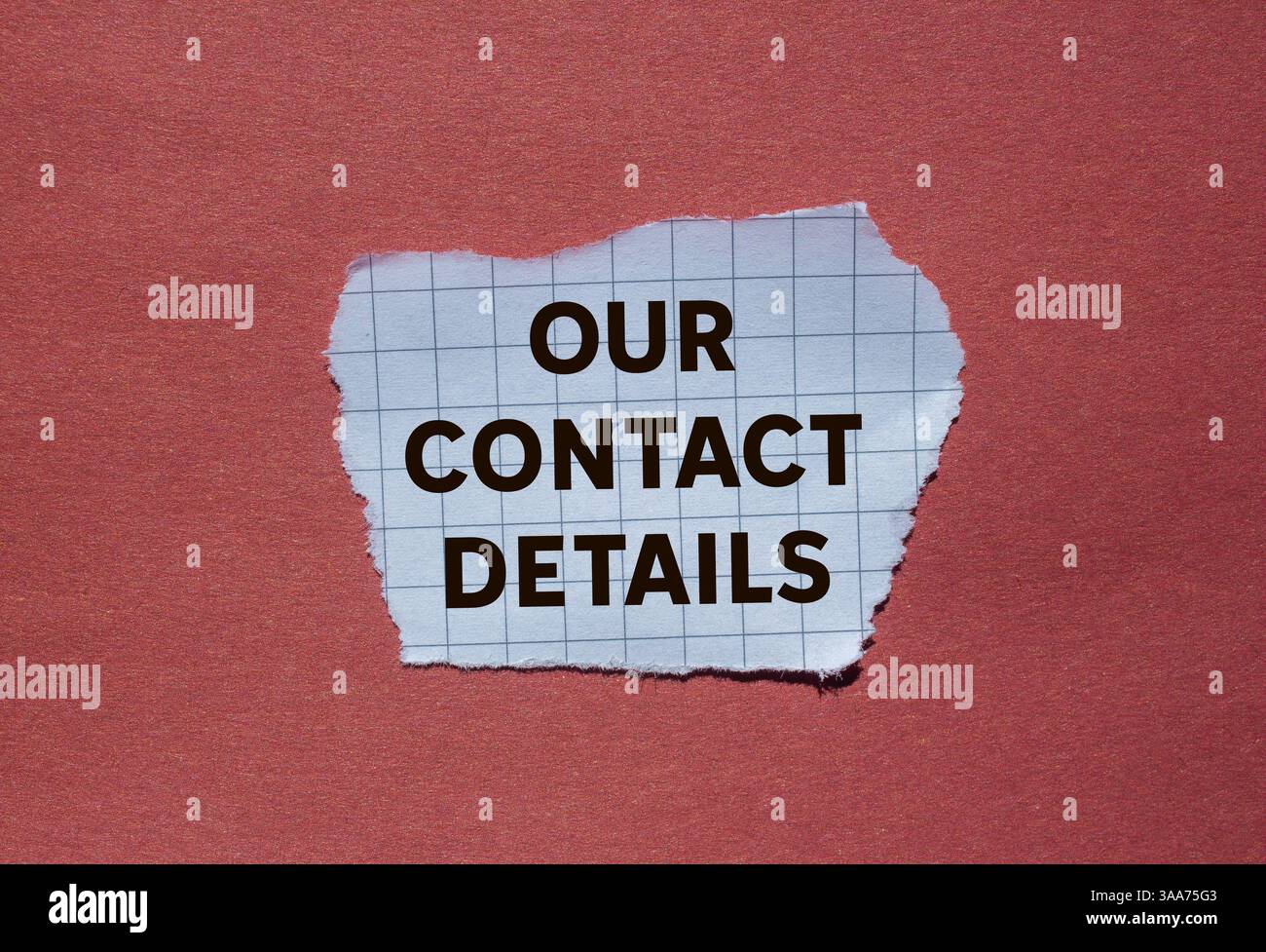 Our contact details message written on ripped torn white checkered paper piece on red background ...