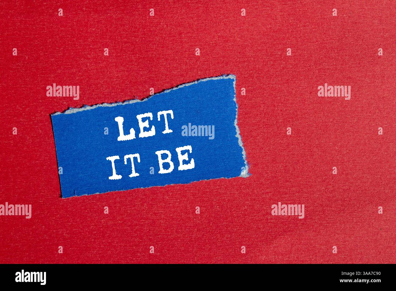 Let it be message written on ripped torn blue paper piece on red ...