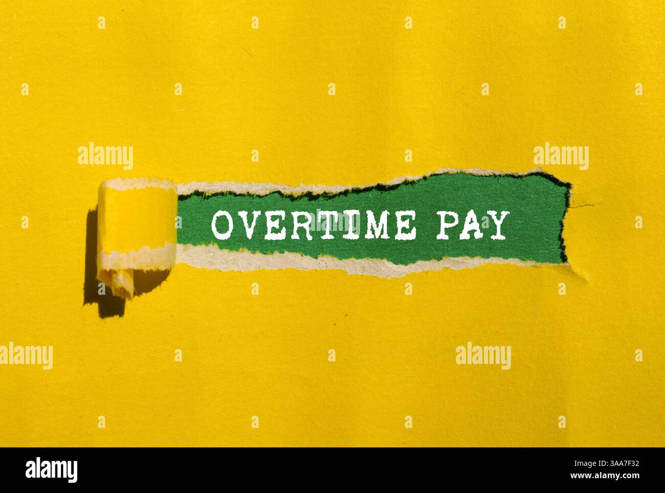 Overtime pay message written on ripped torn yellow paper on green ...