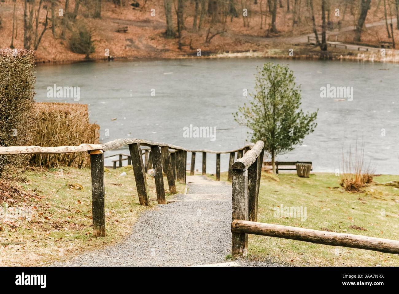 A wooden fence with a stone path leading to a lake. The path is covered ...
