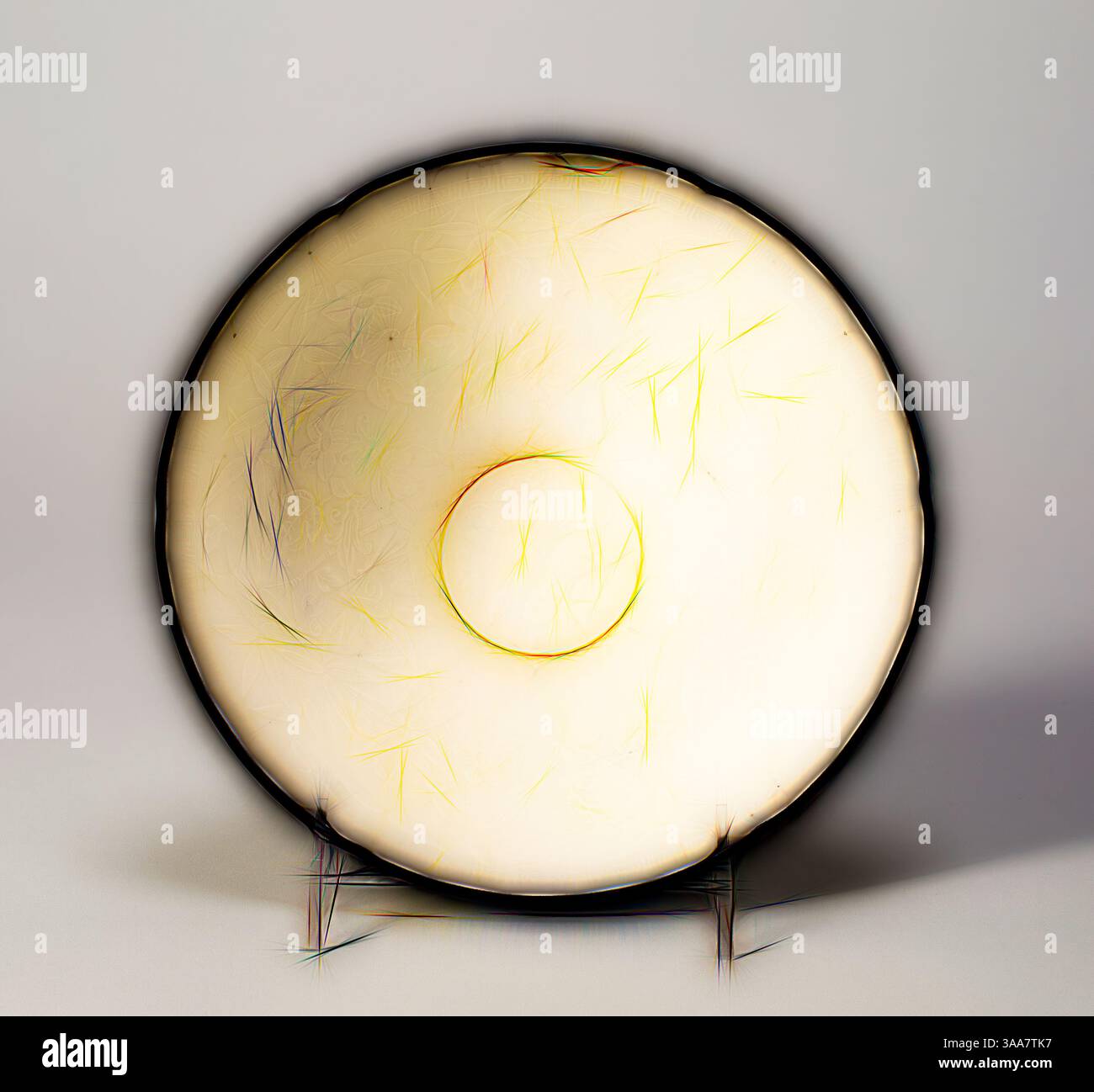 A round, flat disc with a smooth surface and delicate, colorful lines ...