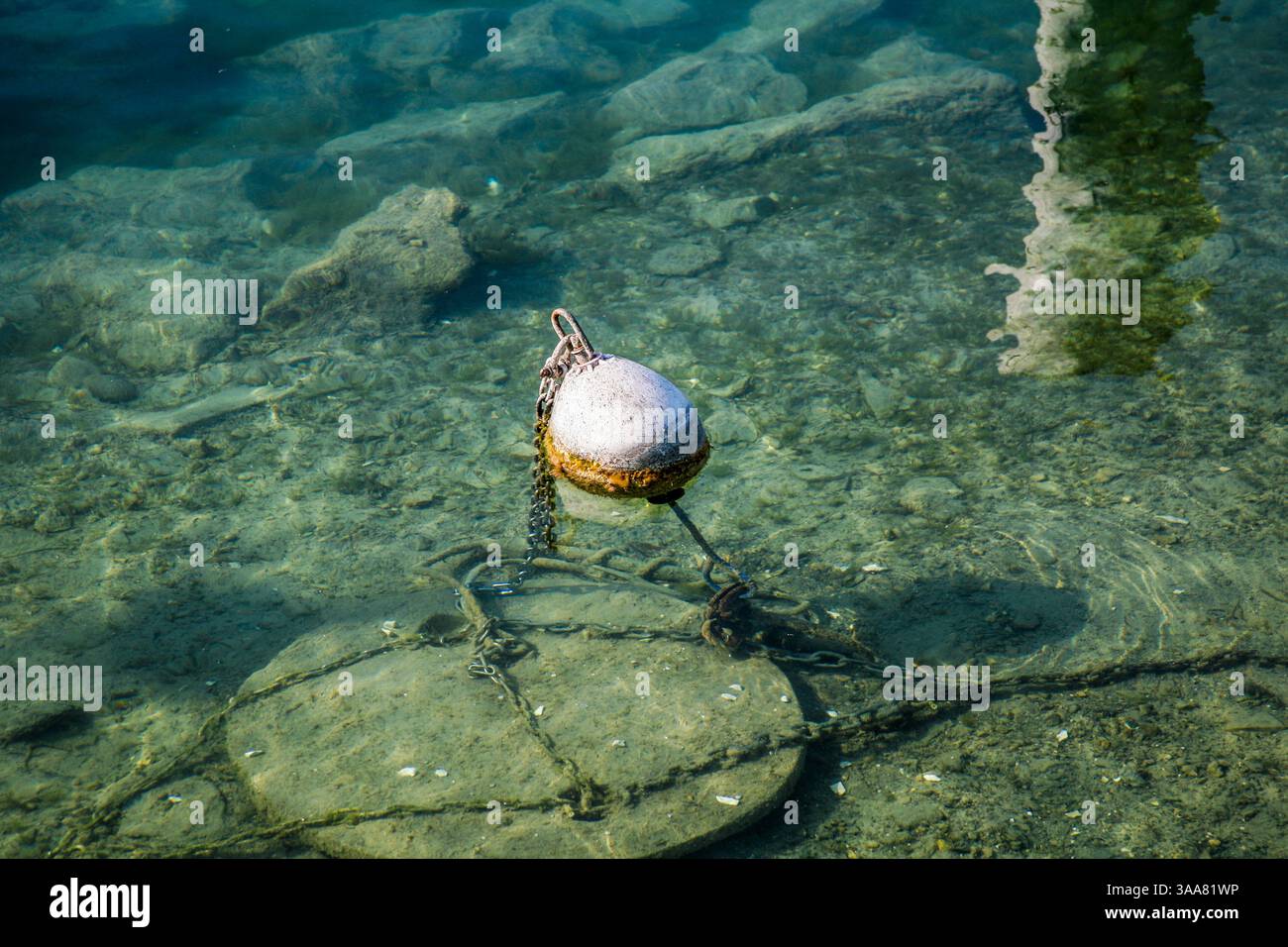 A white object is floating in the water. It is attached to a chain ...