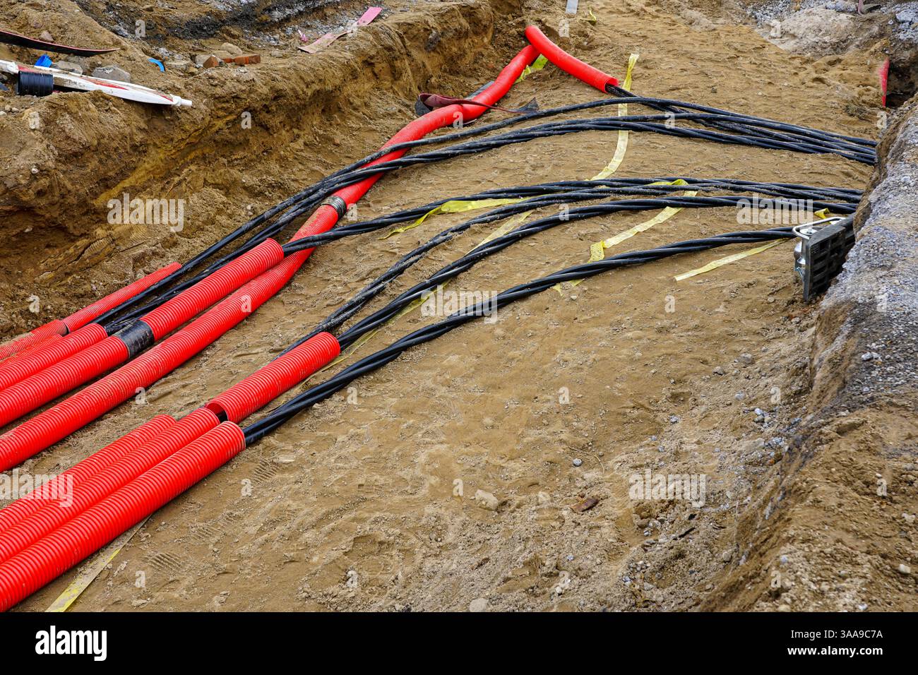 Laying new underground high-voltage power cable in red corrugated ...
