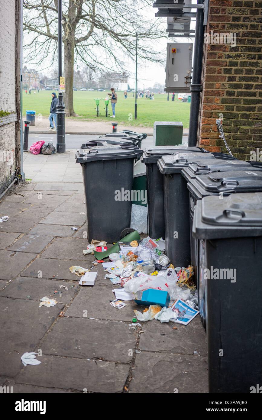 Black refuse bins in an alleyway in south London with garbage on the ...
