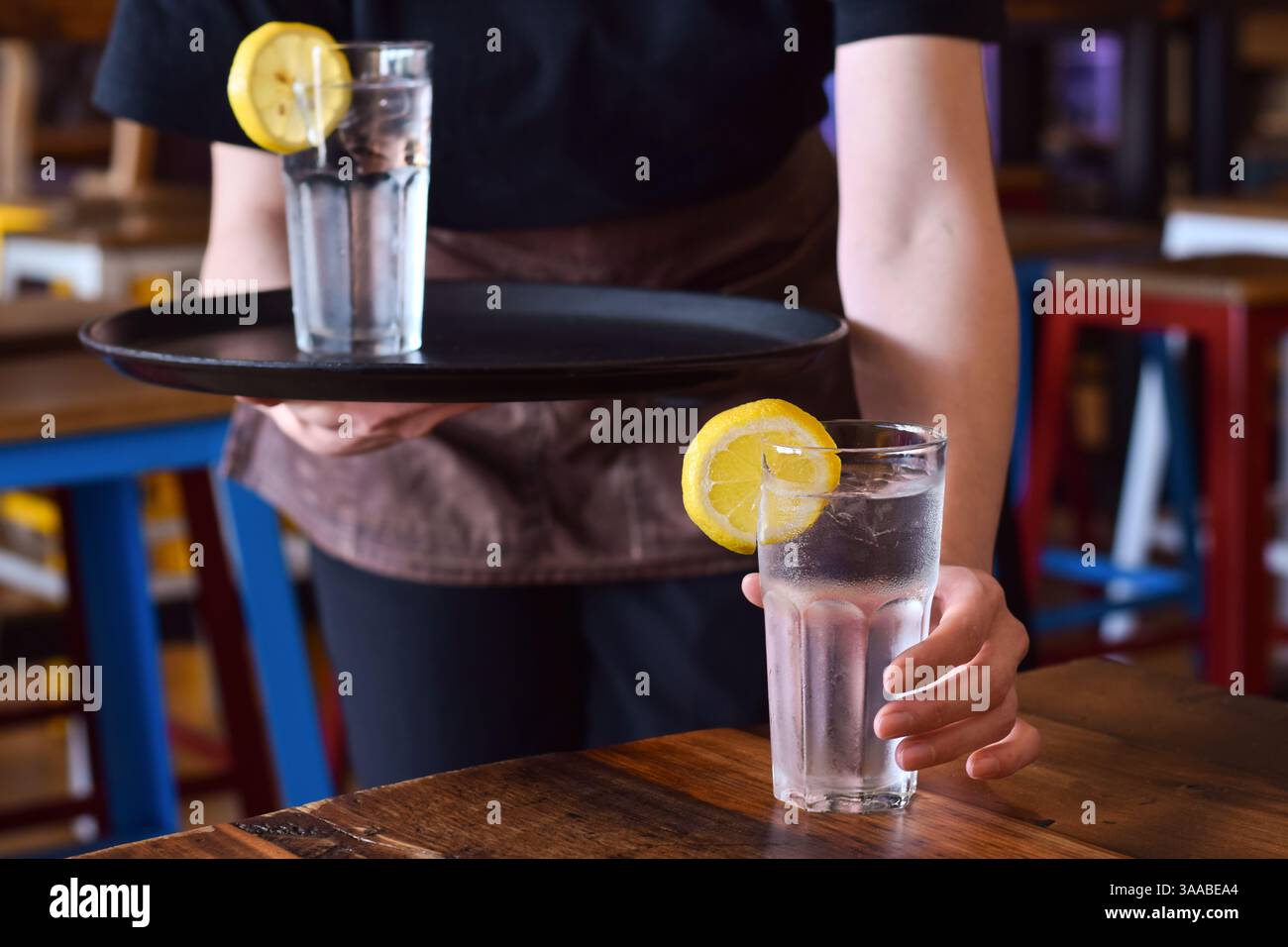 Restaurant server placing glass of cold water with lemon on a table ...
