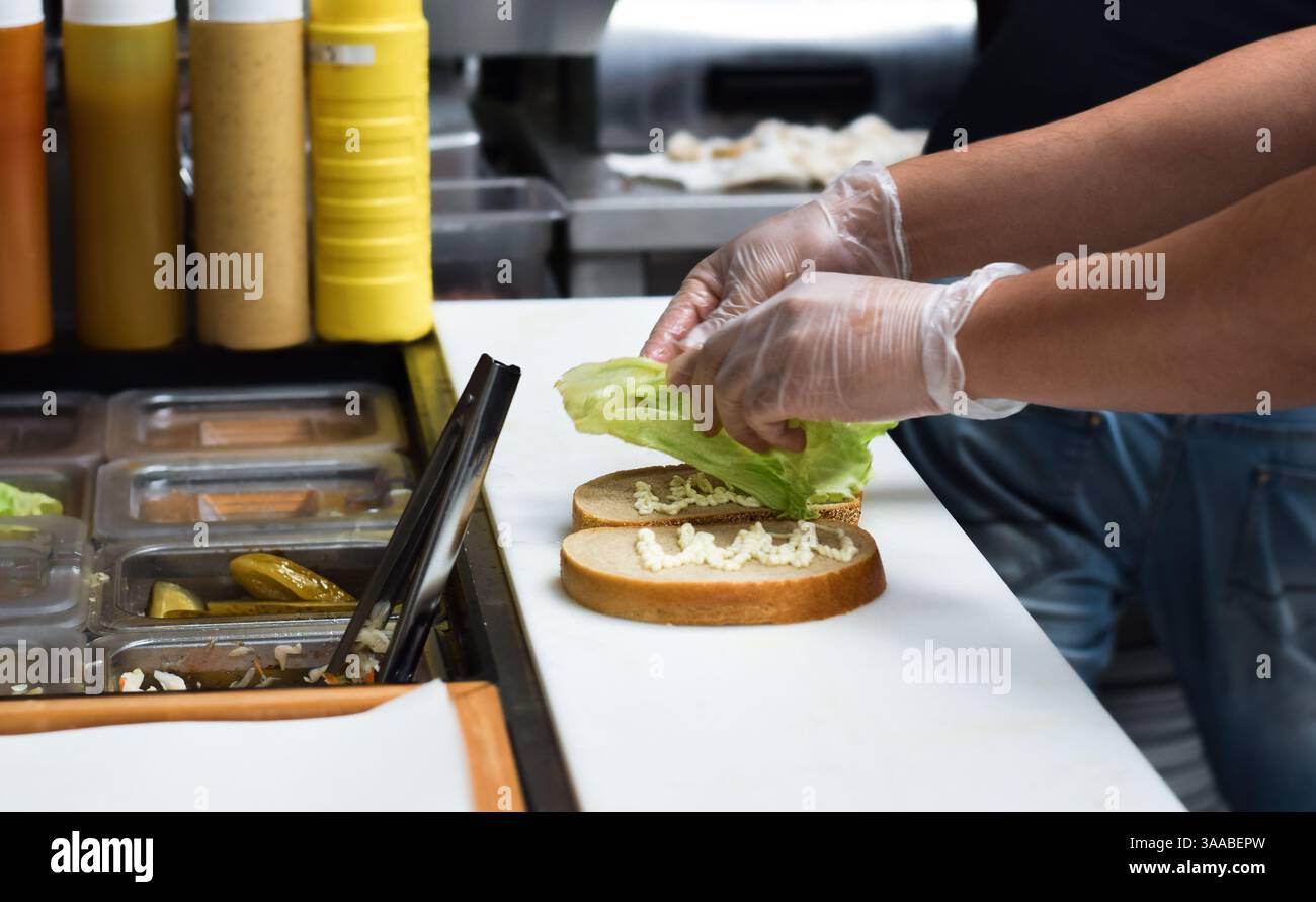 Kitchen employee preparing sandwich for customer food order Stock Photo ...