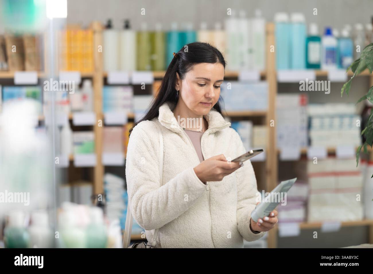 Middle-aged woman scanning QR-code on cream in drugstore Stock Photo ...
