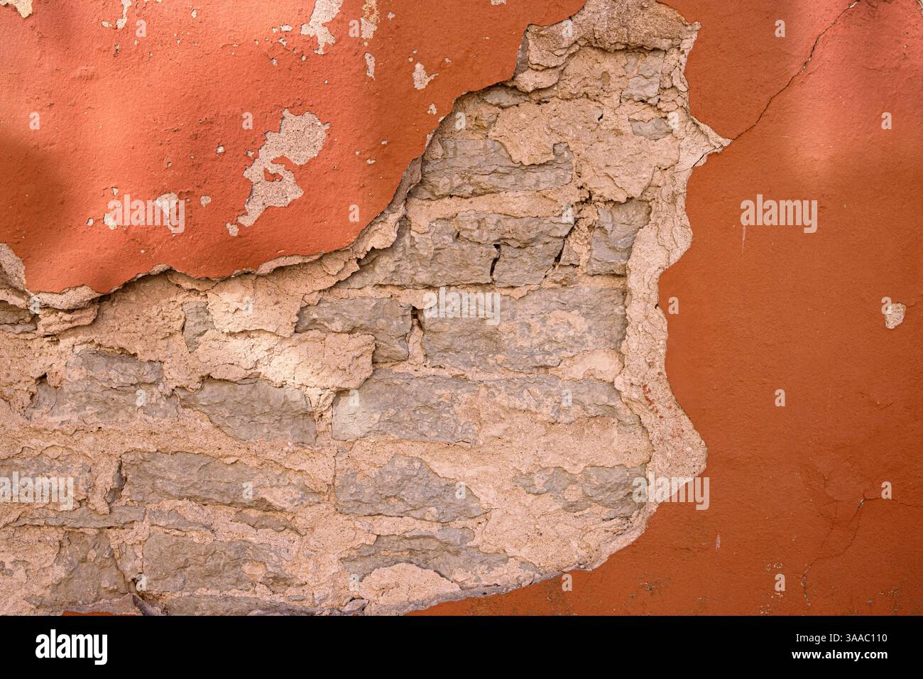 Cracked wall with rustic charm. A detailed close-up of a weathered wall with peeling red paint ...