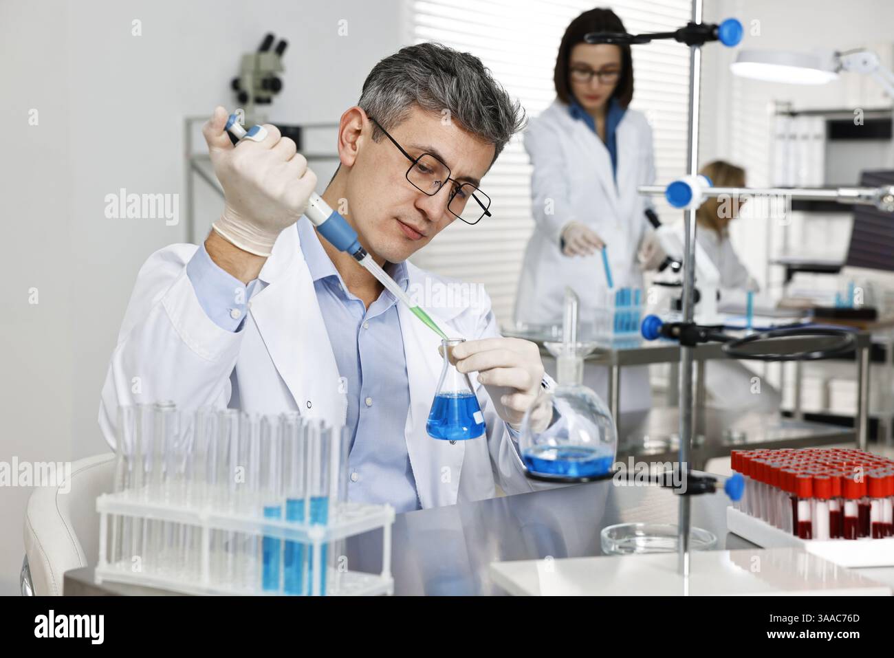 Scientist with micropipette and flask working in laboratory Stock Photo ...