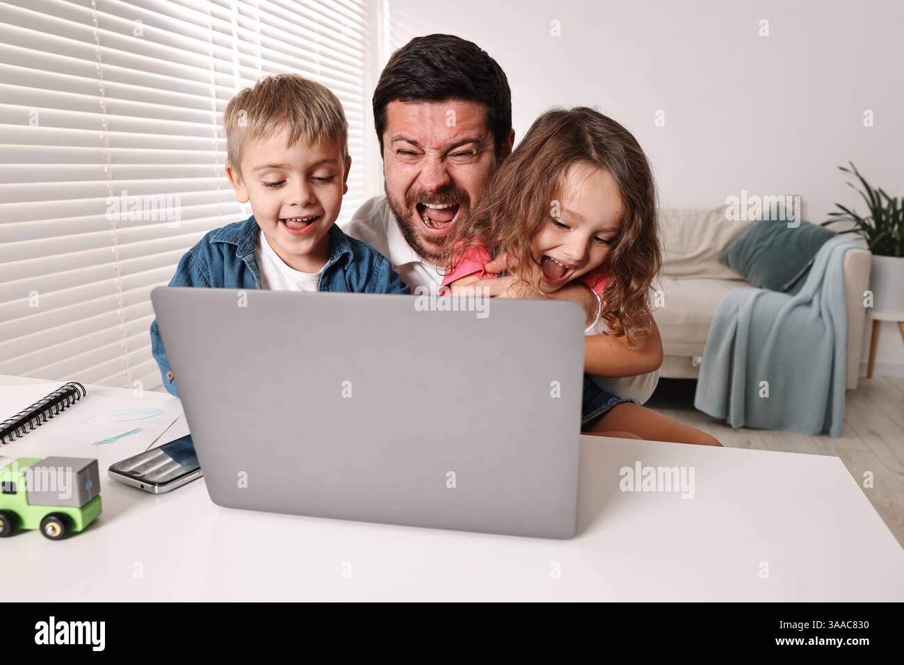 Naughty children disturbing their overwhelmed screaming father at table ...