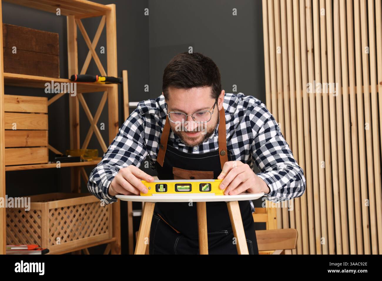 Relaxing hobby. Man using level tool while repairing stool in workshop ...