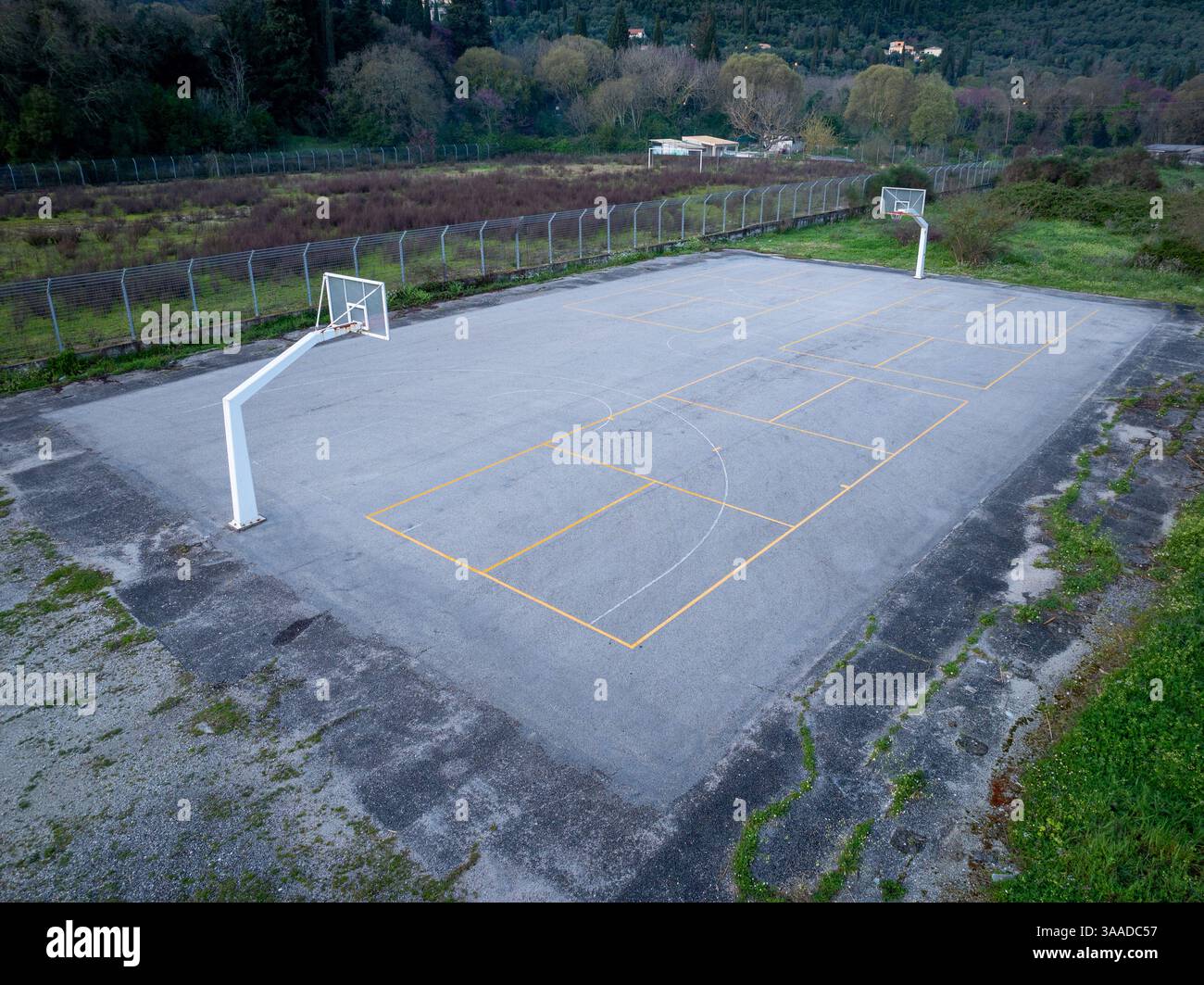 An aerial shot of a rectangular concrete basketball court with faded ...