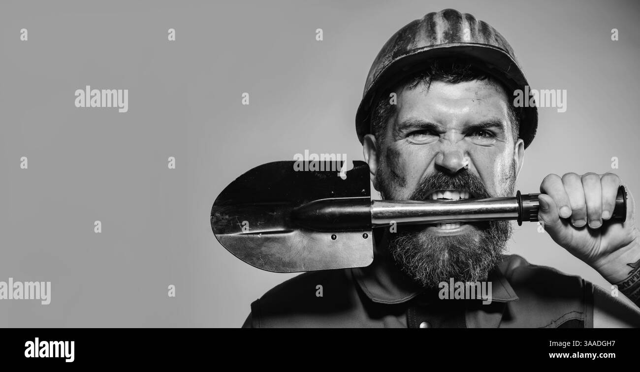 Male builder or miner in protective helmet with shovel in teeth. Mining ...