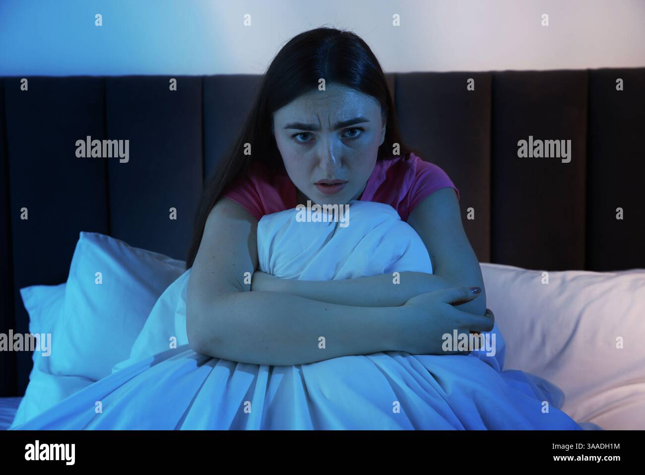 Fear of darkness. Scared young woman on bed in room at night Stock ...