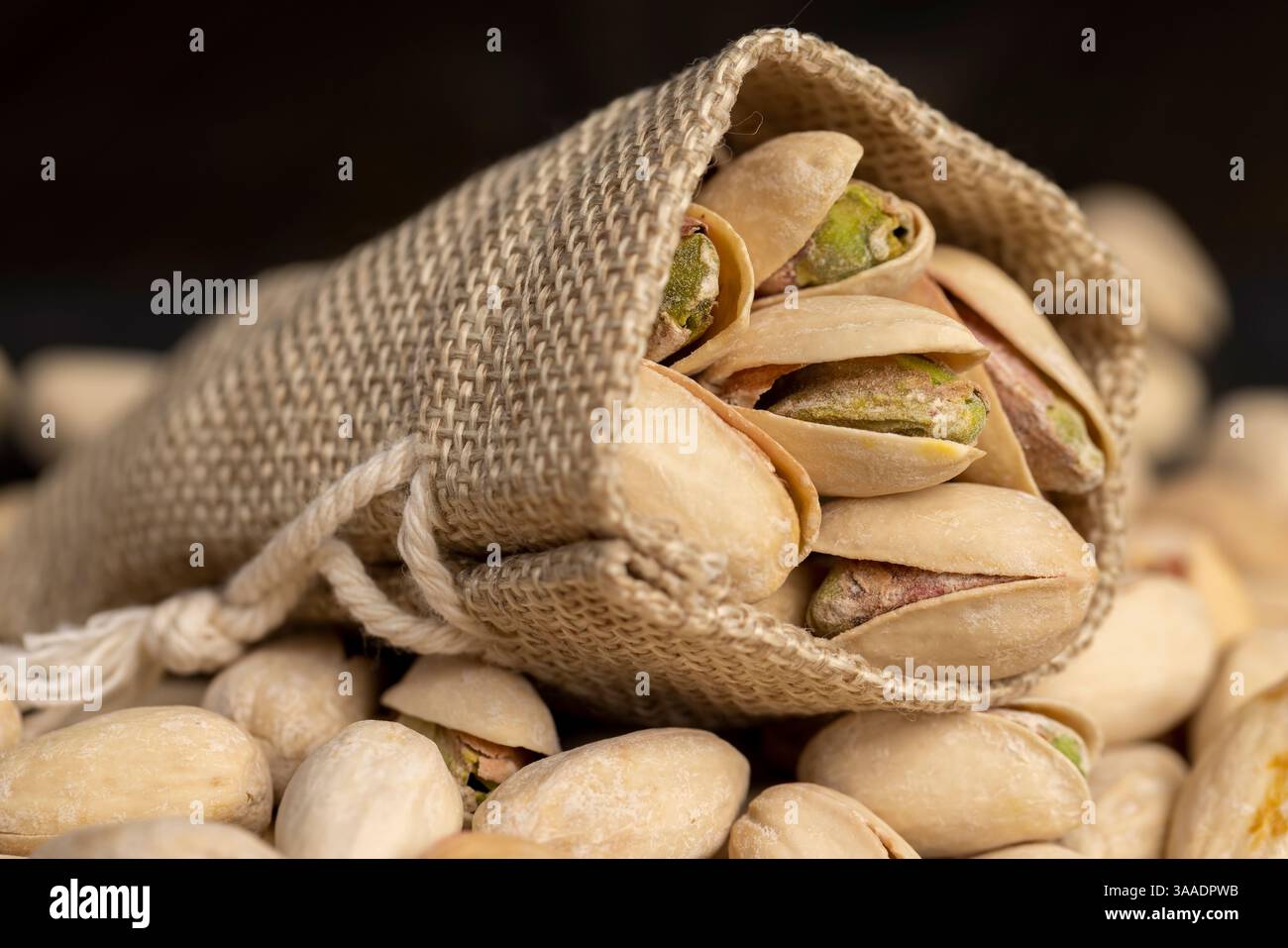 unpeeled pistachio nuts with cracked shells, poured into a coarse bag ...