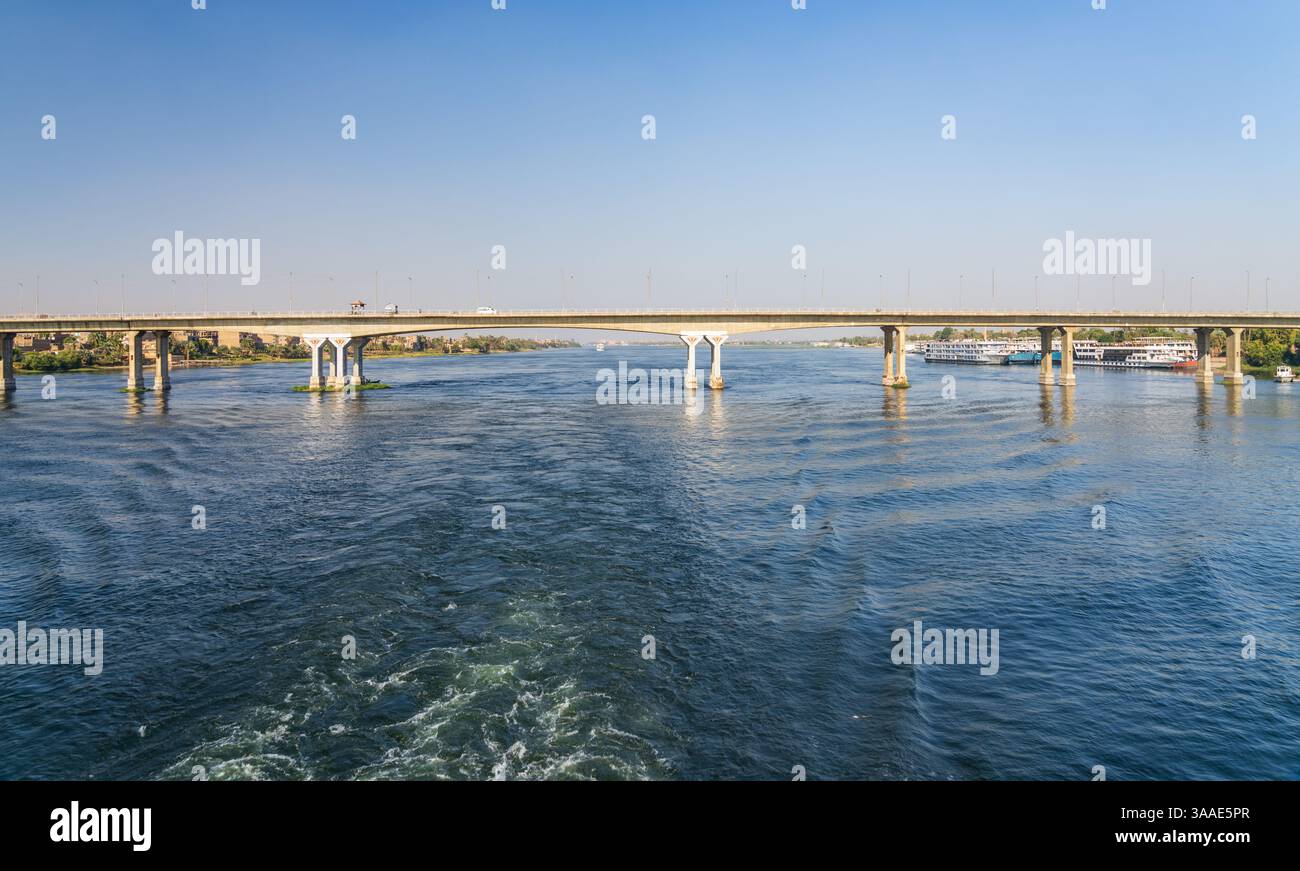 River cruise boat sailing upstream from modern bridge connecting east ...