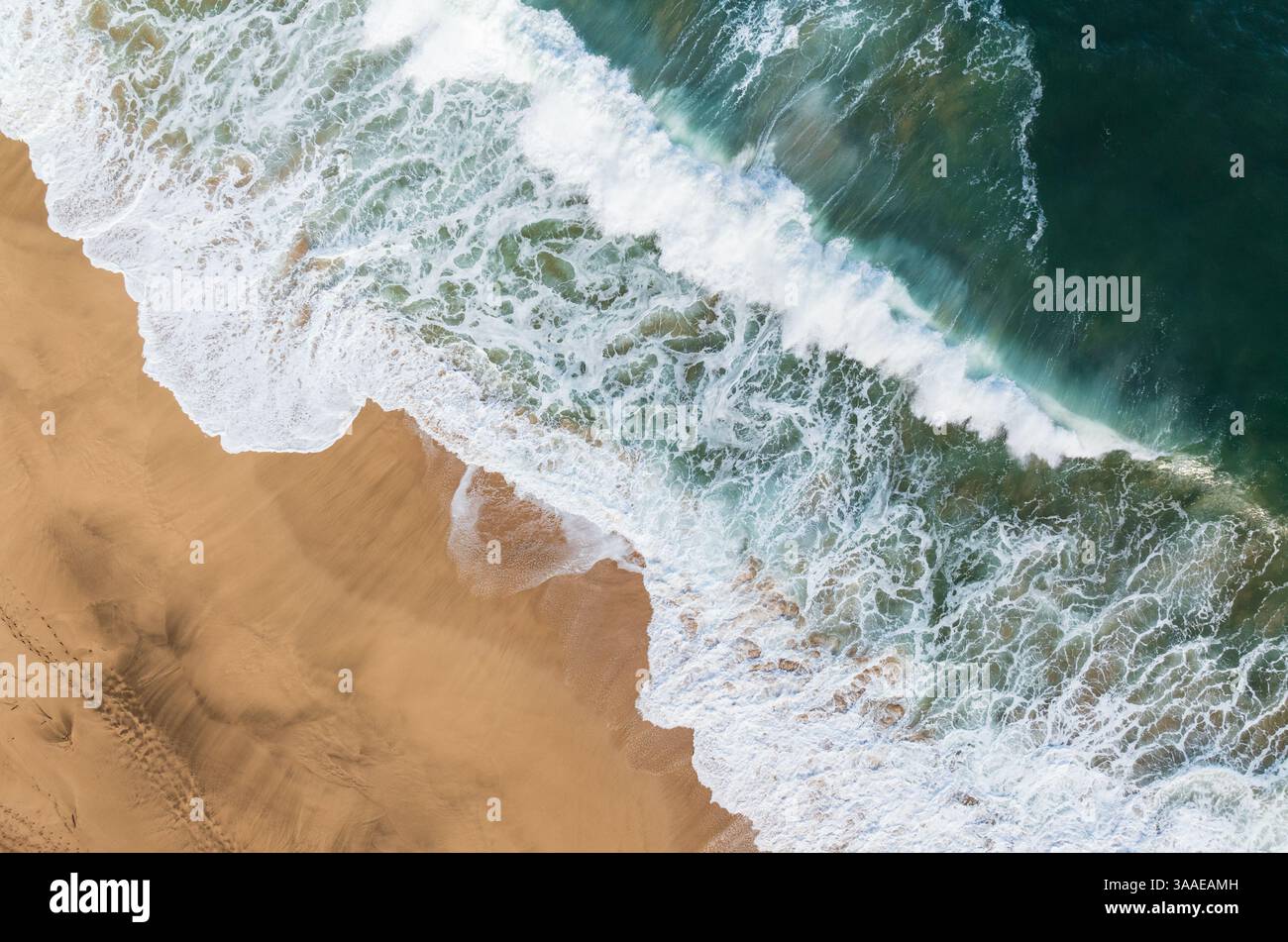 A high-angle shot captures the ocean's powerful waves crashing onto the ...