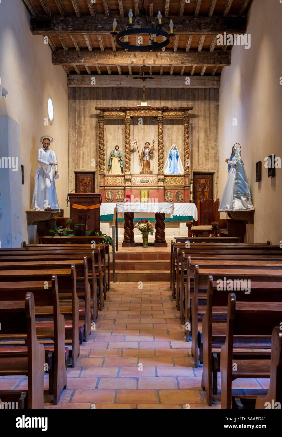 Inside the Mission San Juan church with rows of wooden benches leading ...