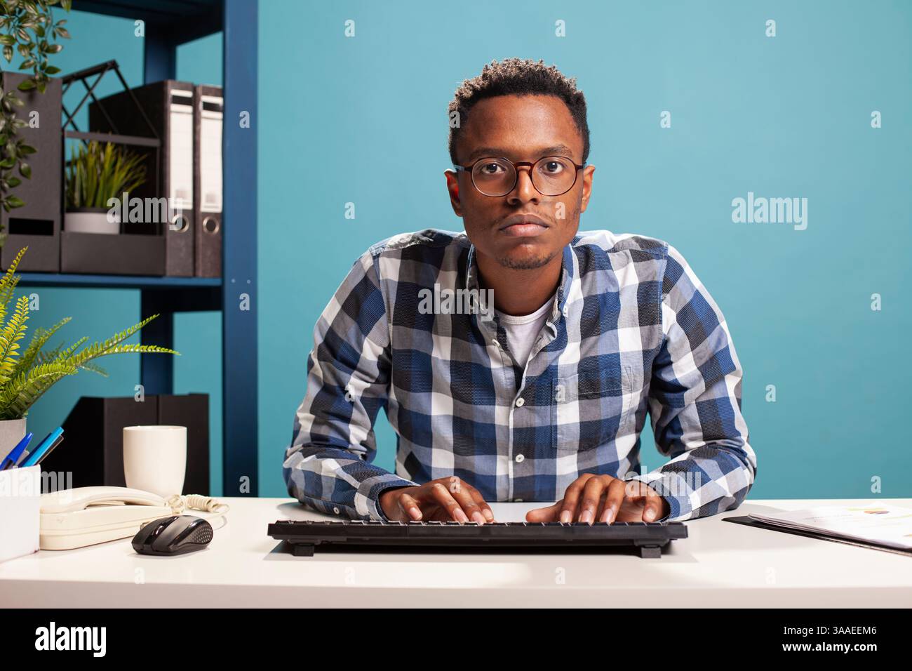 Serious male manager leaning at his office desk, typing on his computer ...